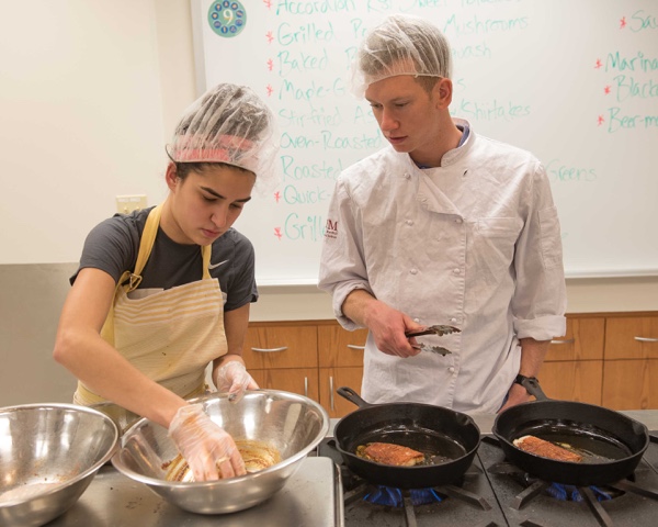 Food management students cooking fish on a cooktop